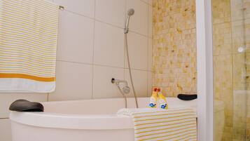 Um banheiro com banheira, chuveiro e parede revestida de azulejos.
