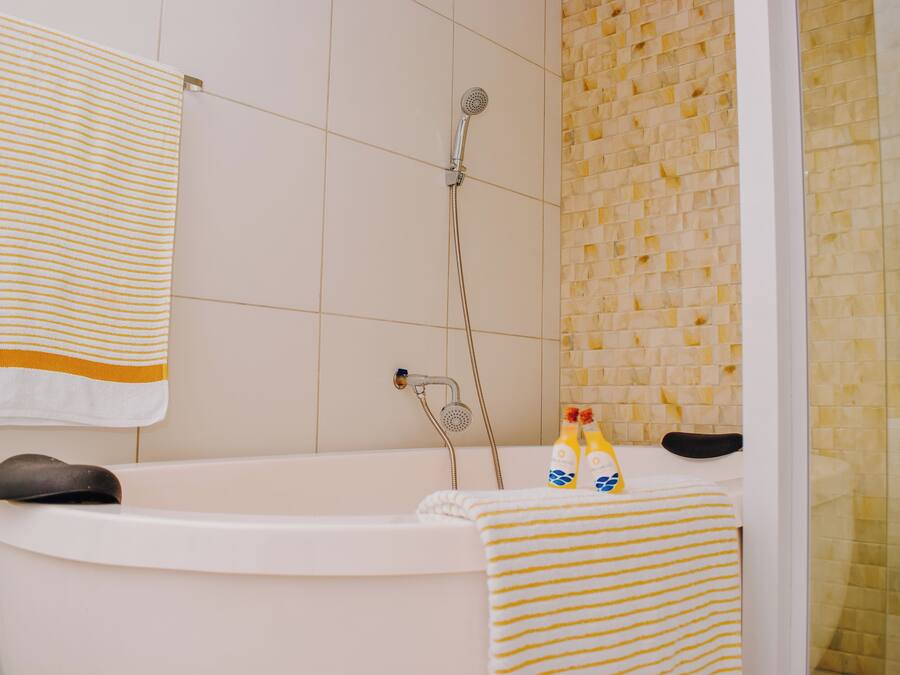 Um banheiro com banheira, chuveiro e parede revestida de azulejos.