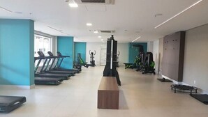 Uma academia com esteiras, máquina de pesos e colchonetes de exercício.