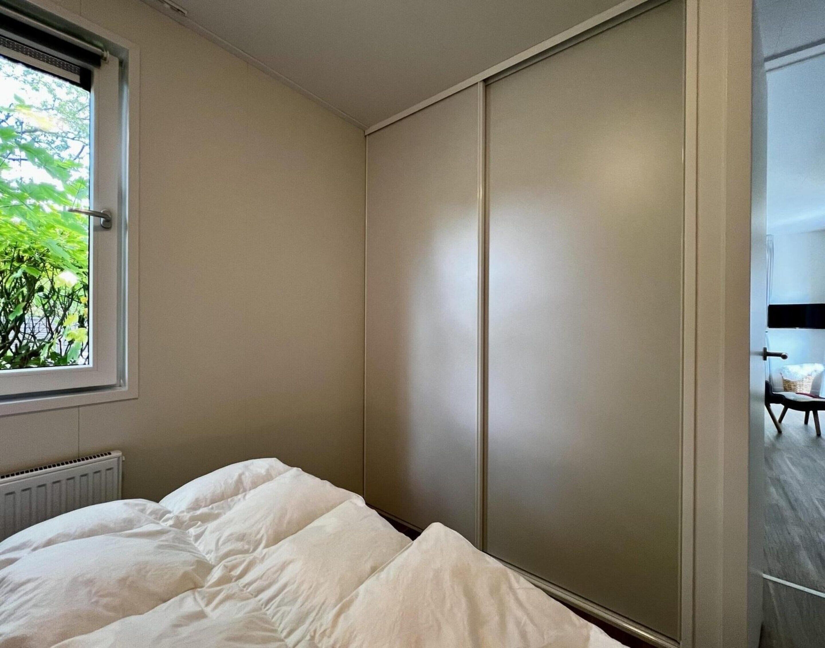 Quarto com uma cama, janela e guarda-roupa.