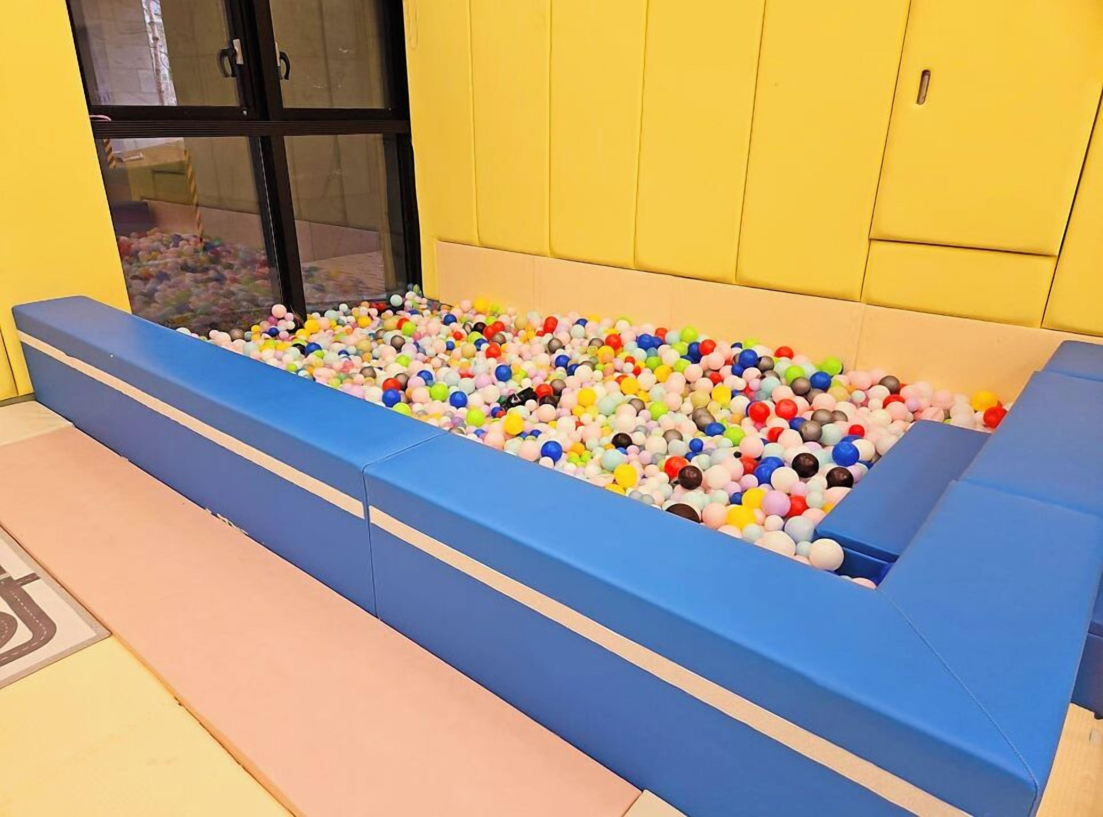 Uma área de recreação com piscina de bolinhas e assentos acolchoados.