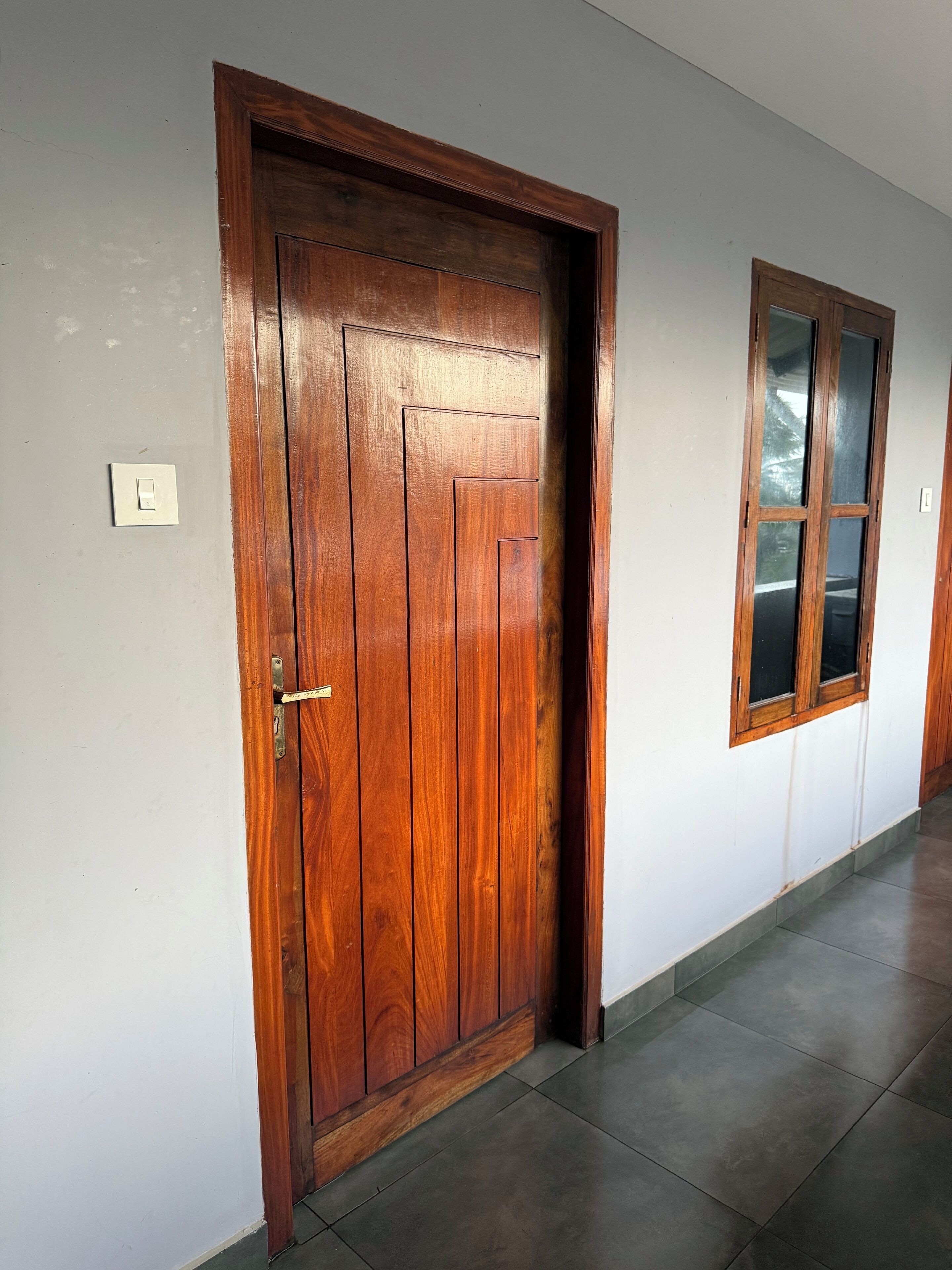 Uma porta de madeira com puxador de latão e janela com moldura de madeira.