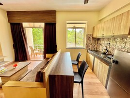 Cozinha moderna com armários de madeira, área de refeições com banco e cadeiras, e vista para o verde lá fora.