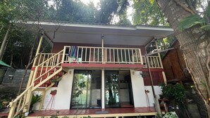 Uma casa de dois andares com varanda, escada e vários vasos de plantas.