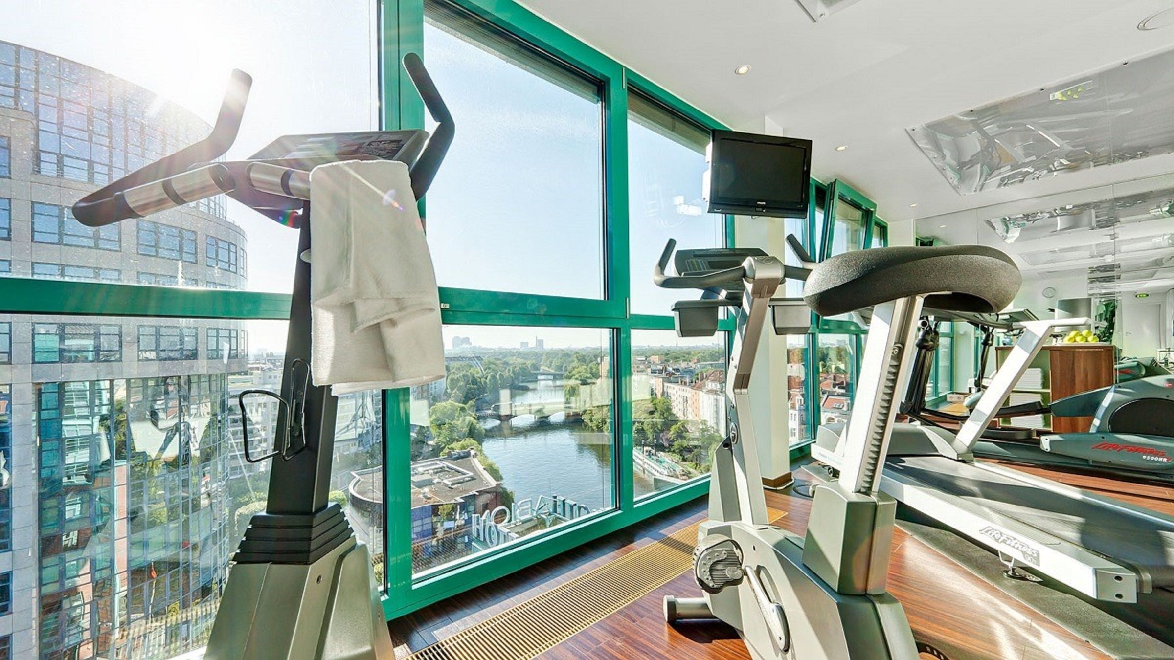Uma academia com equipamentos de ginástica e uma grande janela com vista para a cidade.
