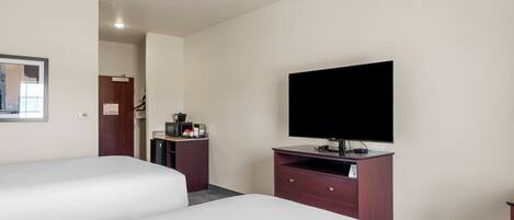Quarto de hotel com duas camas, televisão, escrivaninha com micro-ondas e um pequeno frigorífico.