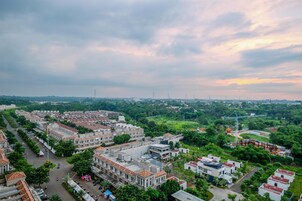 Vista aérea de um bairro residencial com mistura de edifícios tradicionais e modernos, uma avenida central e vegetação ao redor.