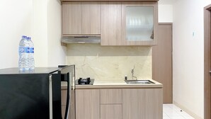 Cozinha compacta com armários de madeira, pia de aço inoxidável e forno embutido.