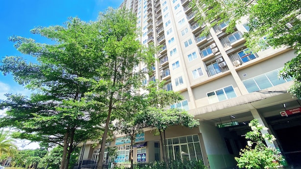 Um edifício alto com várias varandas e uma árvore verde em primeiro plano.