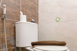 Casa de banho com sanita, toalha e suporte para papel higiénico.