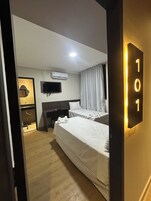 Quarto de hotel com duas camas, uma escrivaninha, uma televisão e um aparelho de ar condicionado.