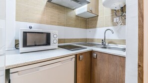 Uma cozinha moderna com micro-ondas, fogão, pia e armários de madeira.