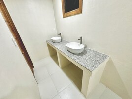 Casa de banho com duas pias, um espelho e uma janela pequena.