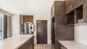 Uma cozinha moderna com bancada de mármore, armários de madeira, frigorífico encastrado e um espelho grande.