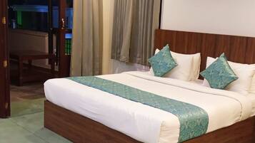 Cama bem arrumada com cabeceira de madeira, roupa de cama branca e almofadas decorativas verde-água.
