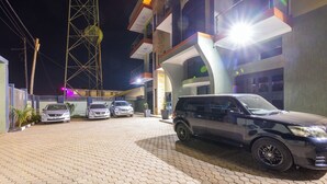 Uma área de estacionamento com vários carros, um edifício de design moderno e uma grande estrutura de antena.