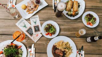 Uma mesa de madeira com vários pratos, bebidas e talheres.