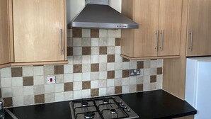Uma cozinha com armários de madeira, fogão a gás e painel de azulejos.