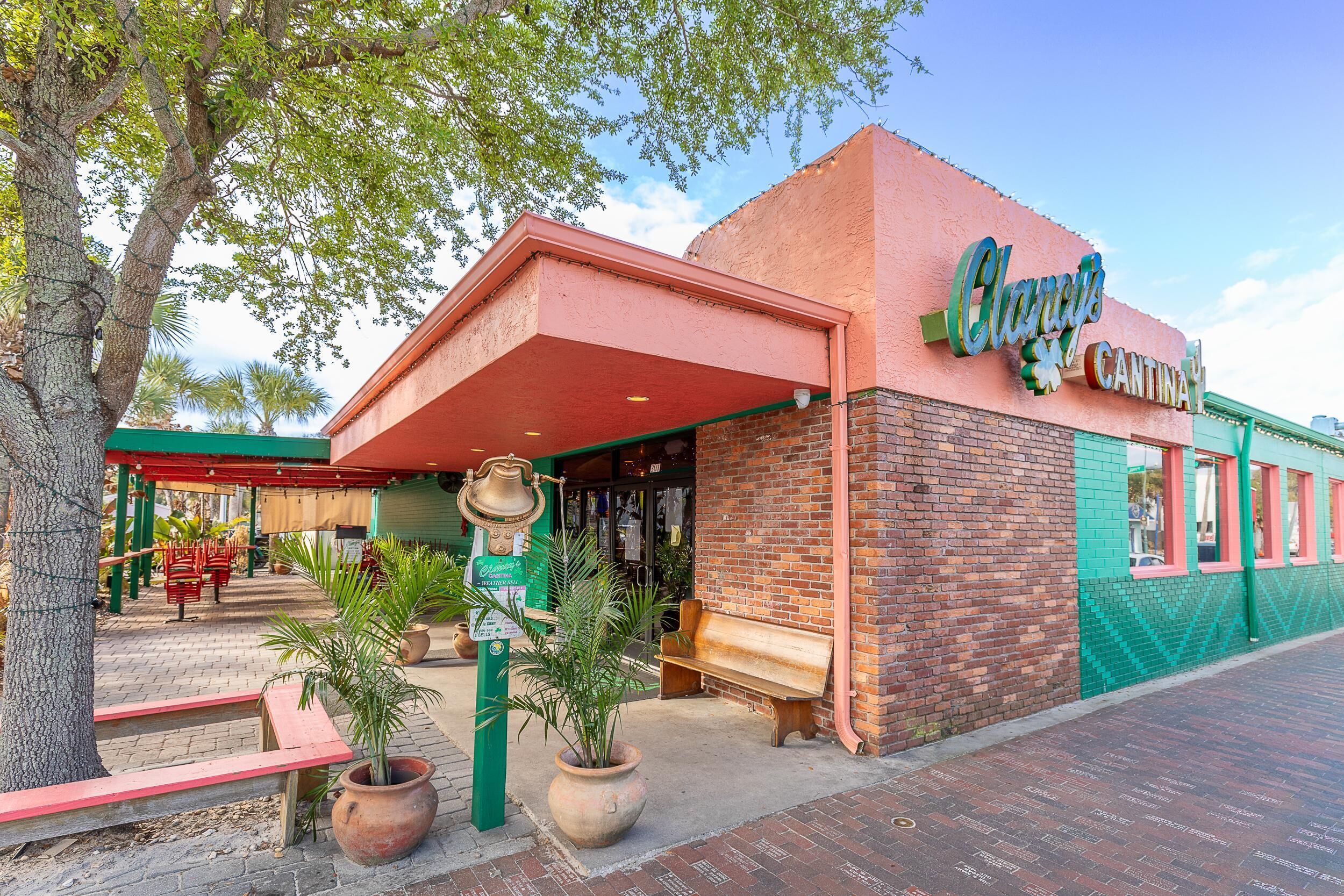 Um restaurante chamado 'Clancy's Cantina' com fachada de tijolos, mesas ao ar livre e plantas em vasos.
