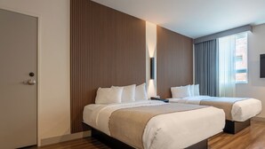 Quarto de hotel com duas camas, parede de painéis de madeira, janela com cortinas e uma porta.