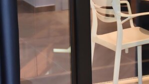 Um interior moderno com divisória de vidro, uma cadeira branca e uma mesa redonda.