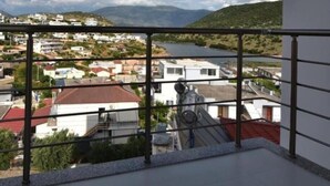 Uma varanda com vista para uma cidade, um corpo d'água e montanhas.