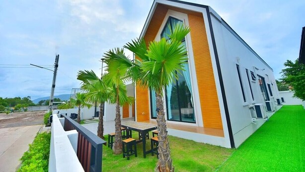 Uma casa moderna de dois andares com telhado inclinado, janelas grandes e um gramado bem cuidado.