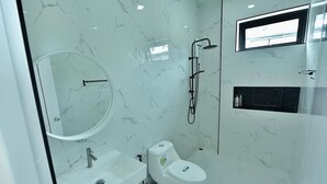 Uma casa de banho moderna com sanita, lavatório e chuveiro.