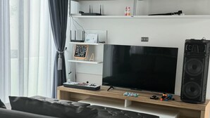 Uma sala de estar moderna com uma televisão de tela plana grande, um móvel para entretenimento de madeira e um sofá de couro preto.