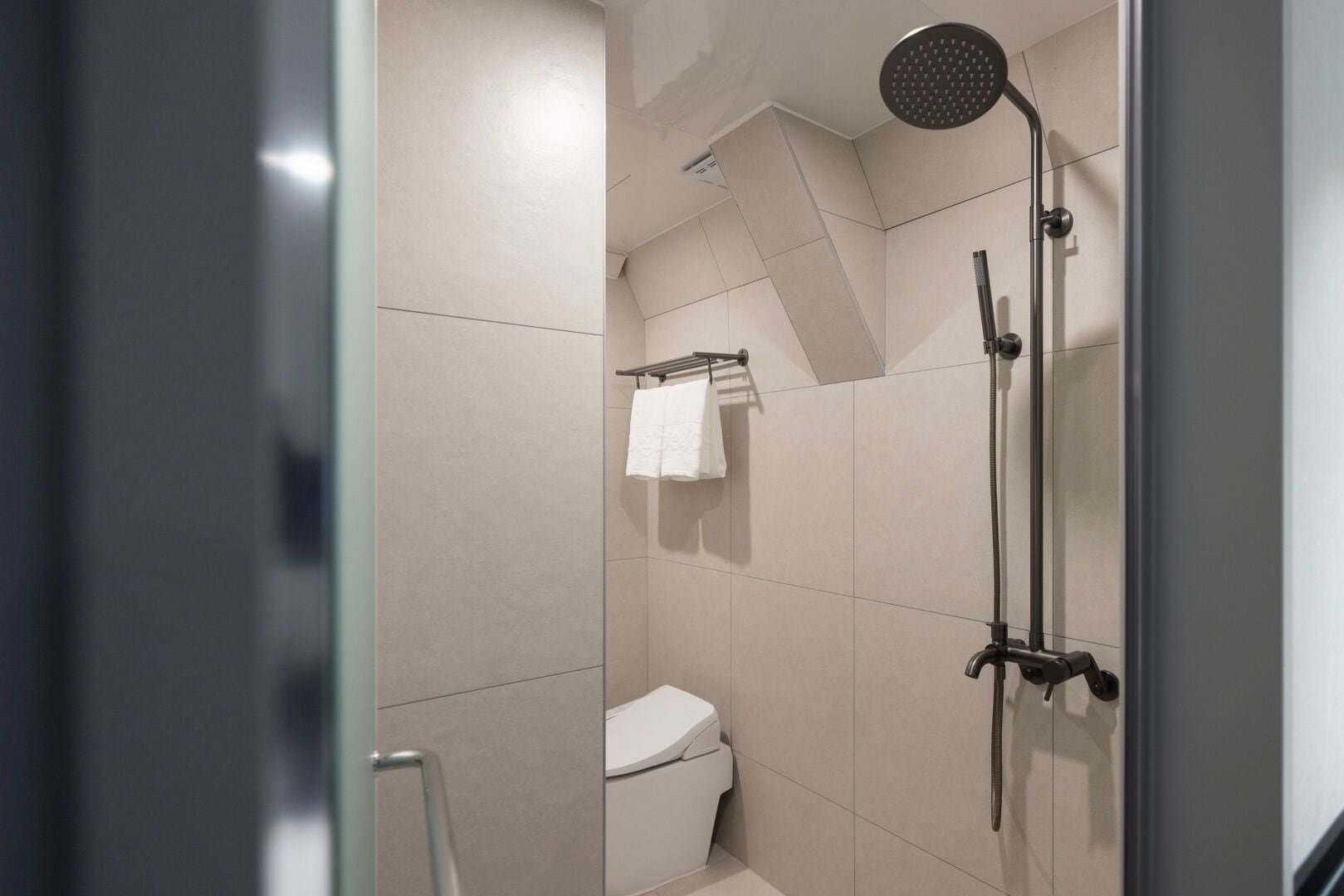 Um banheiro moderno com chuveiro, vaso sanitário e porta-toalhas.