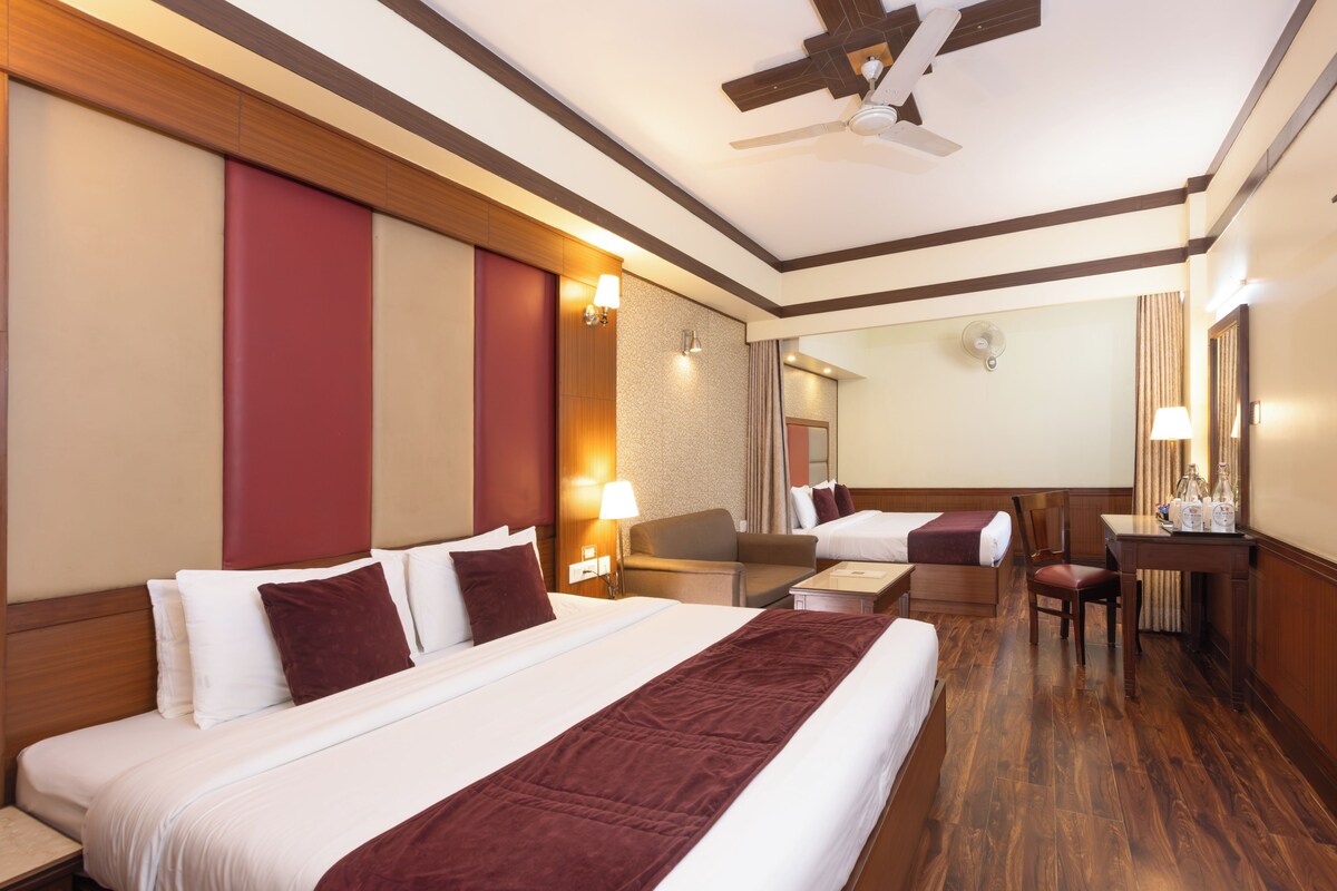 Quarto de hotel com uma cama grande, escrivaninha, cadeira, sofá e ventilador de teto.