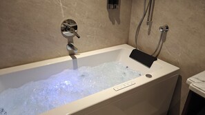 Uma banheira com água corrente, um painel de controle e um chuveiro.