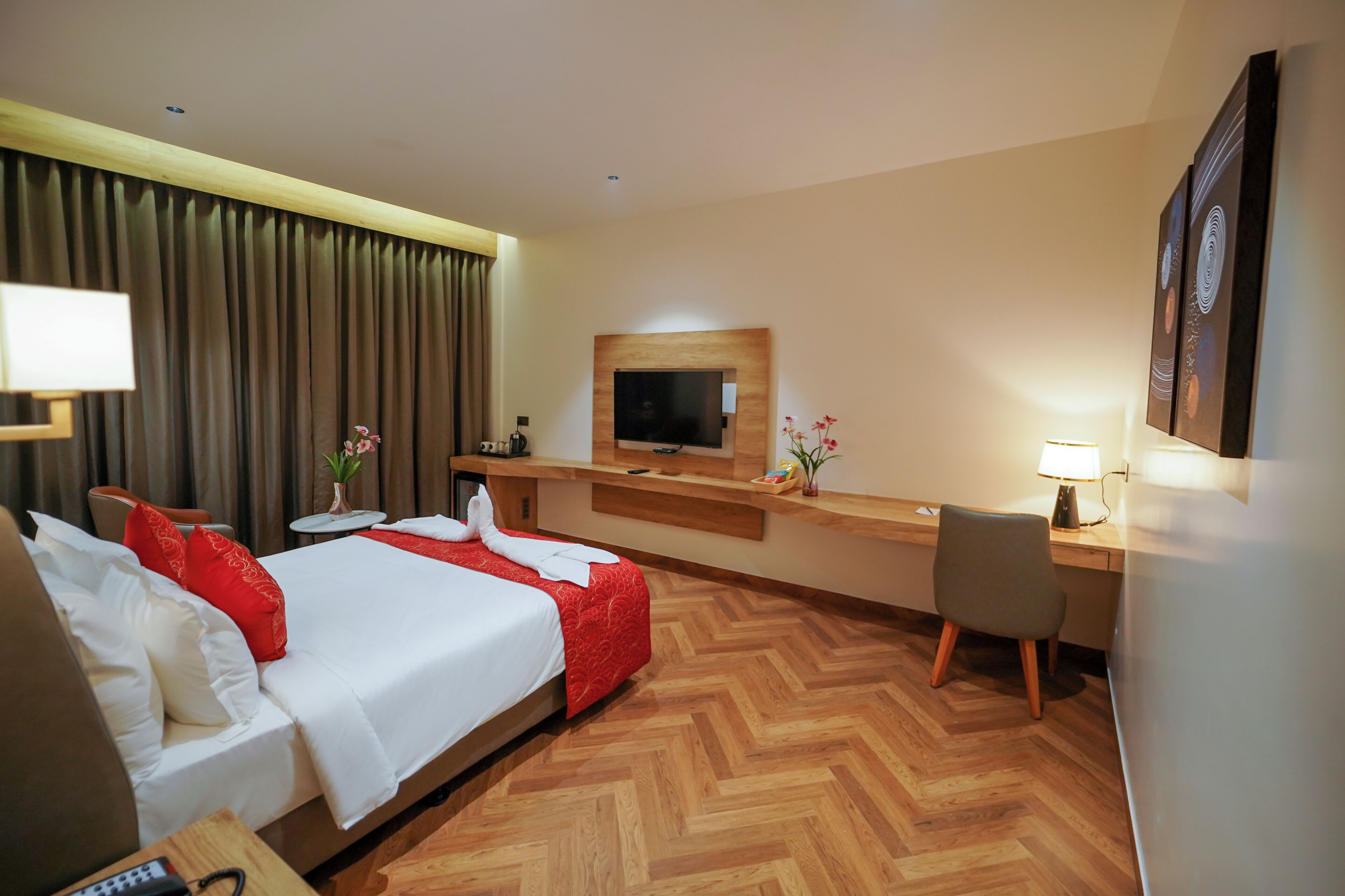 Quarto de hotel com uma cama grande, uma escrivaninha, uma televisão e uma cadeira.