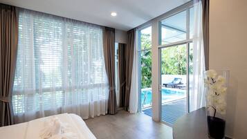 Quarto de hotel com cama, um vaso de flores e vista para uma piscina.