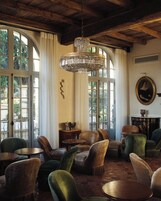 Um quarto com janelas amplas, um lustre e móveis antigos.