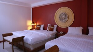 Quarto de hotel com duas camas, mesa de cabeceira, abajur e um objeto decorativo na parede.