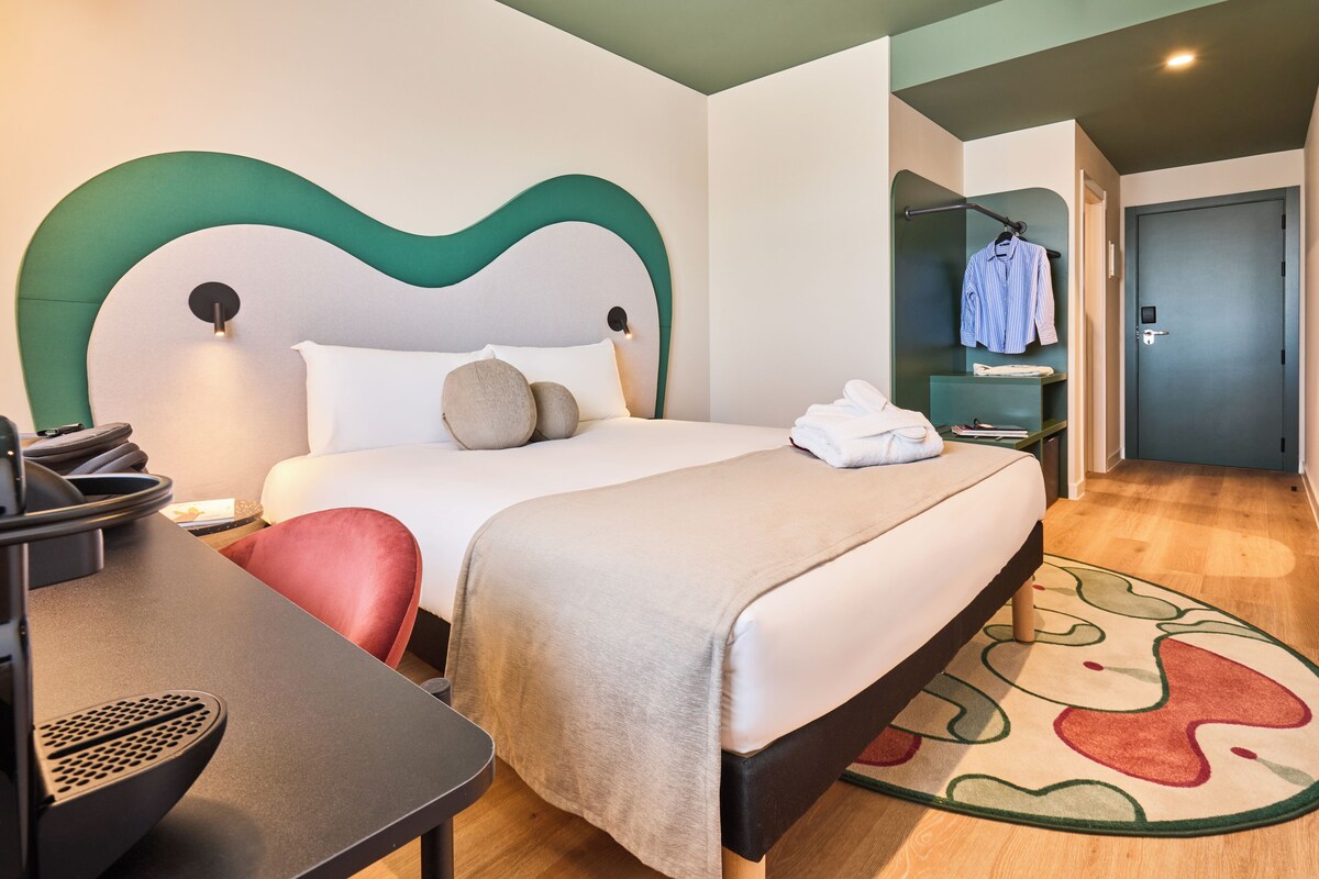 Quarto de hotel bem arrumado, com uma cama, uma mesa e uma cadeira.