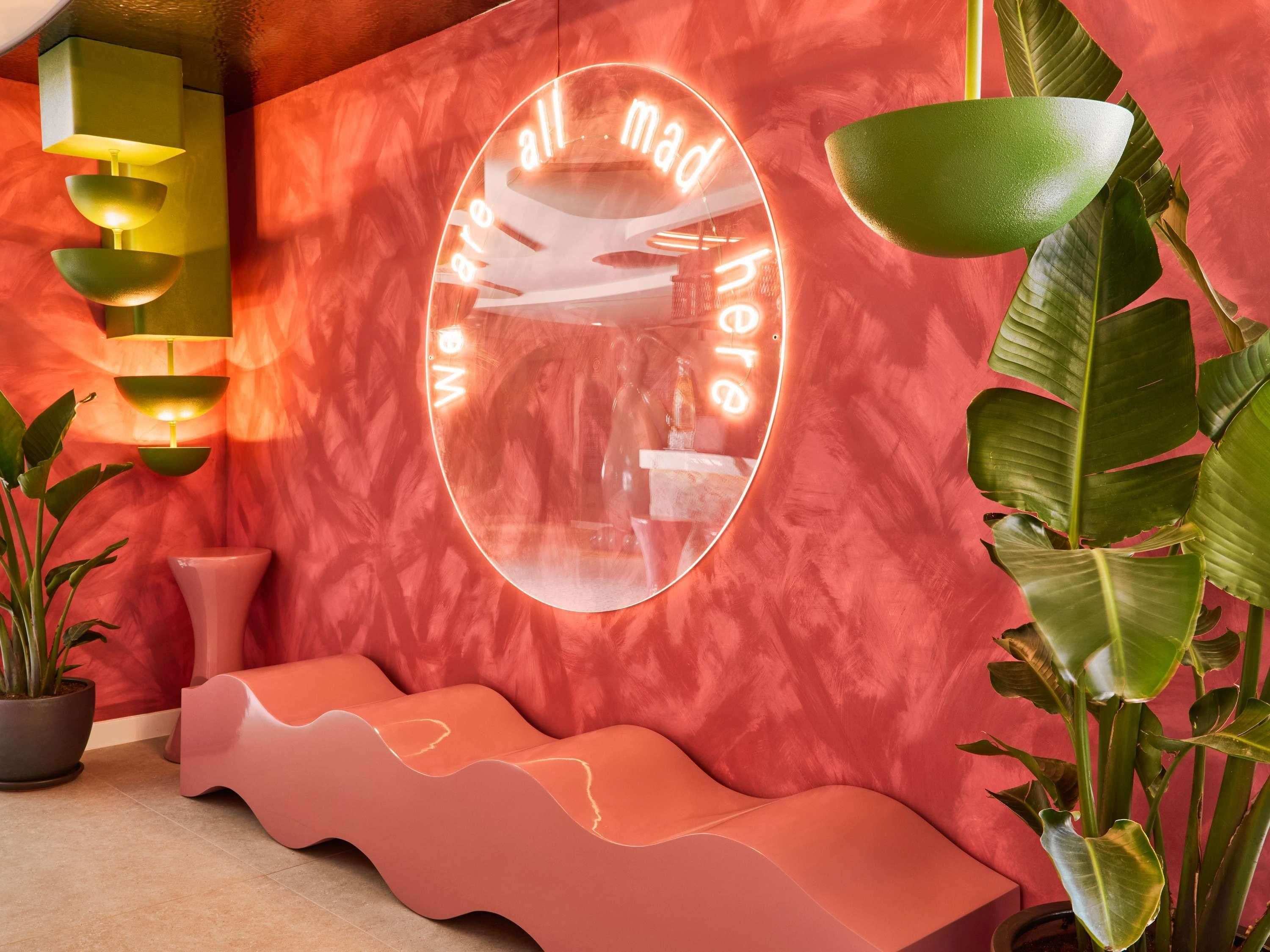 Um interior moderno com uma parede espelhada, uma área de estar diferenciada e uma planta verde.