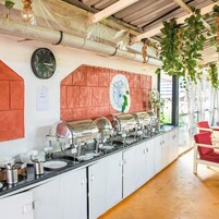 Disposição de buffet com várias estações de comida, um relógio e uma parede decorativa com motivos florais.