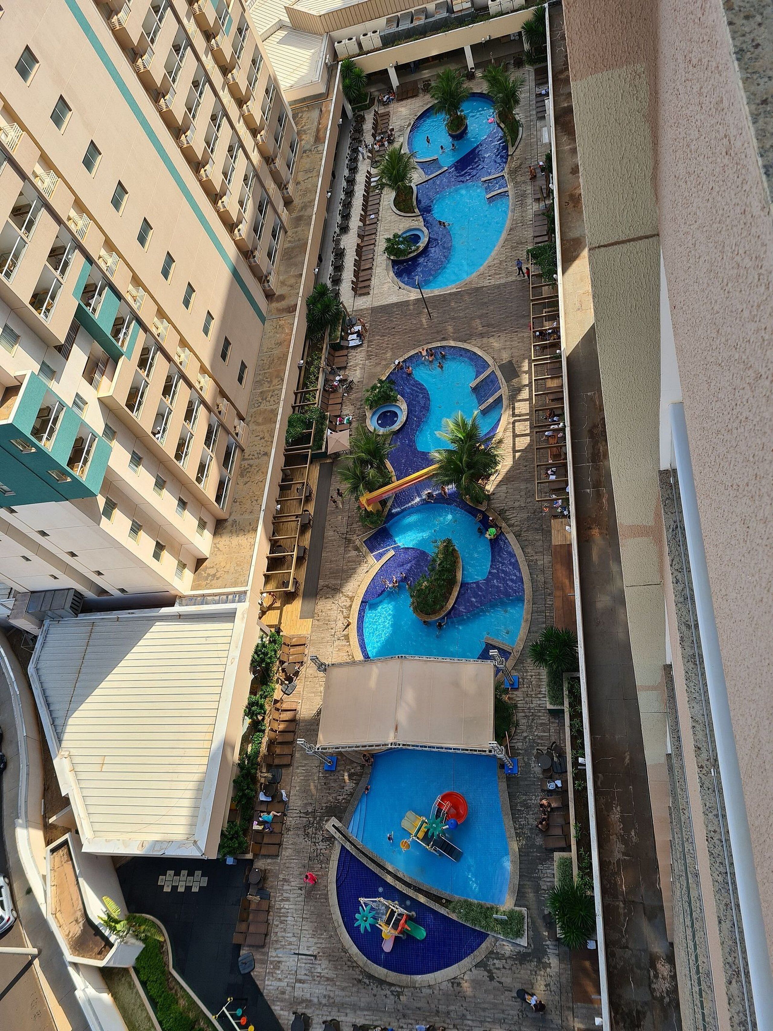 Hotel com vários níveis e área de piscina no terraço, incluindo várias piscinas e um espaço de recreação infantil.