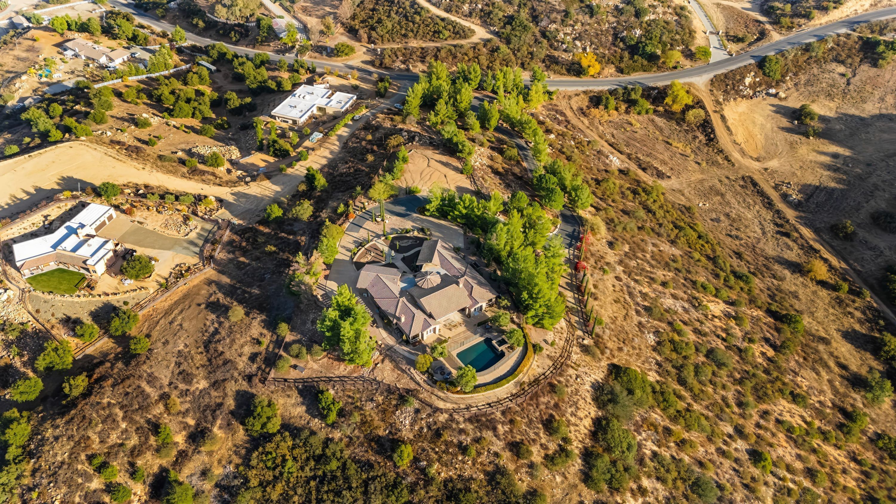 Vista aérea de uma área residencial com várias casas, uma piscina e paisagismo bem cuidado.