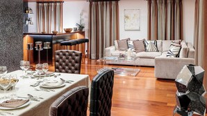 Uma sala de estar moderna com área de jantar, apresentando um sofá, cadeiras, uma mesa de centro e uma mesa de jantar posta para uma refeição.