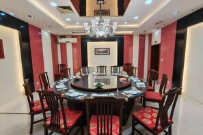 Uma sala de conferências com uma mesa redonda, cadeiras e um lustre.