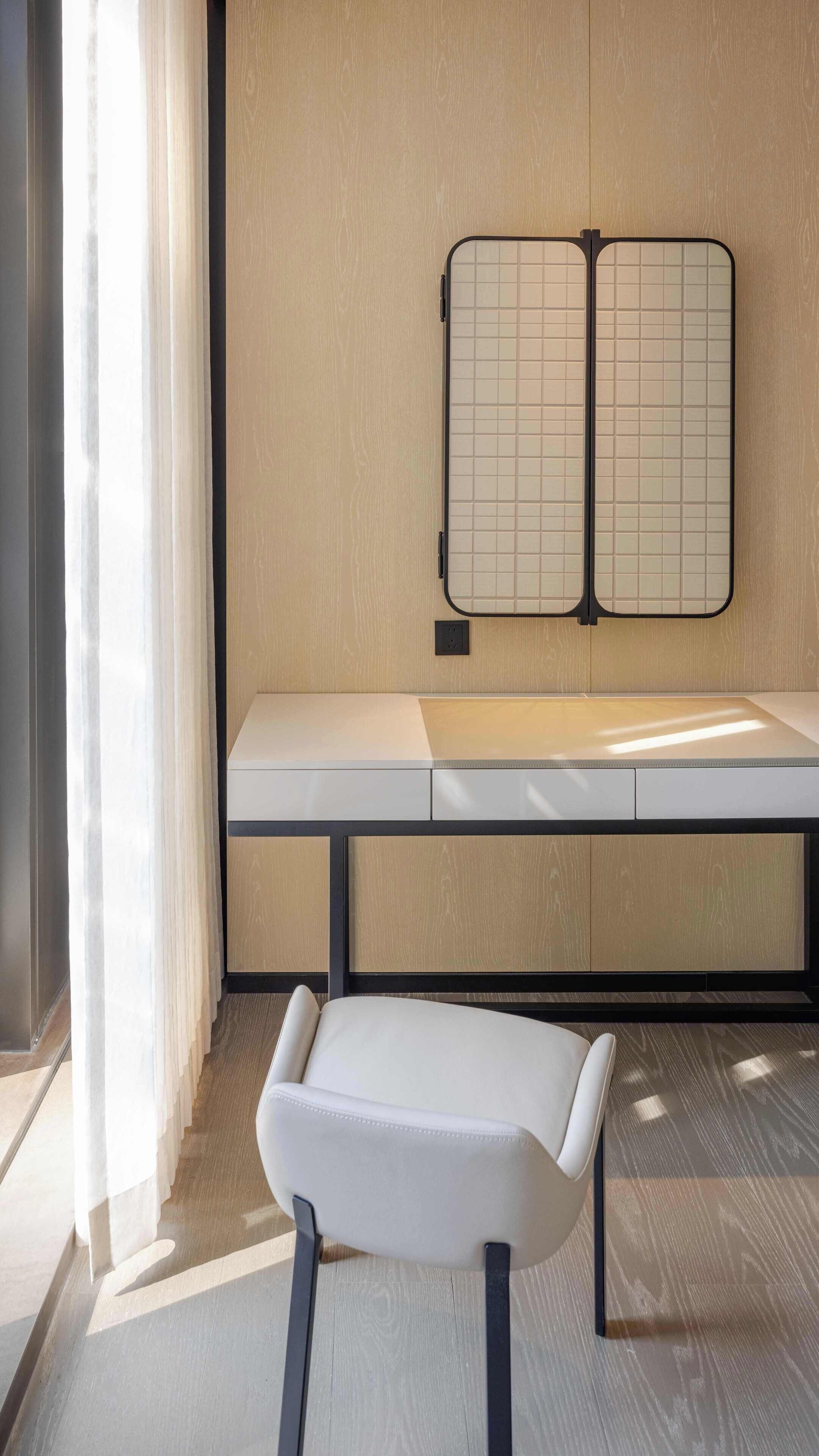 Quarto moderno com piso de madeira, um banco branco e um objeto em forma de grade fixado na parede.
