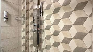 Um chuveiro moderno com parede de azulejos geométricos, chuveiro manual e torneira embutida.