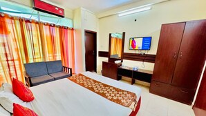 Quarto de hotel com uma cama, um sofá, uma mesa, uma televisão e um guarda-roupa.