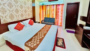 Quarto de hotel com uma cama grande, um sofá, uma TV e um guarda-roupa.