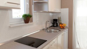 Uma cozinha moderna com pia embutida, cafeteira e uma fruteira no balcão.
