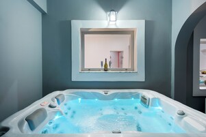 Um banheiro moderno com hidromassagem, espelho fixado na parede e luminária.