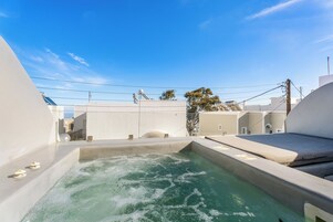 Piscina no terraço com céu azul límpido e edifícios brancos ao fundo.
